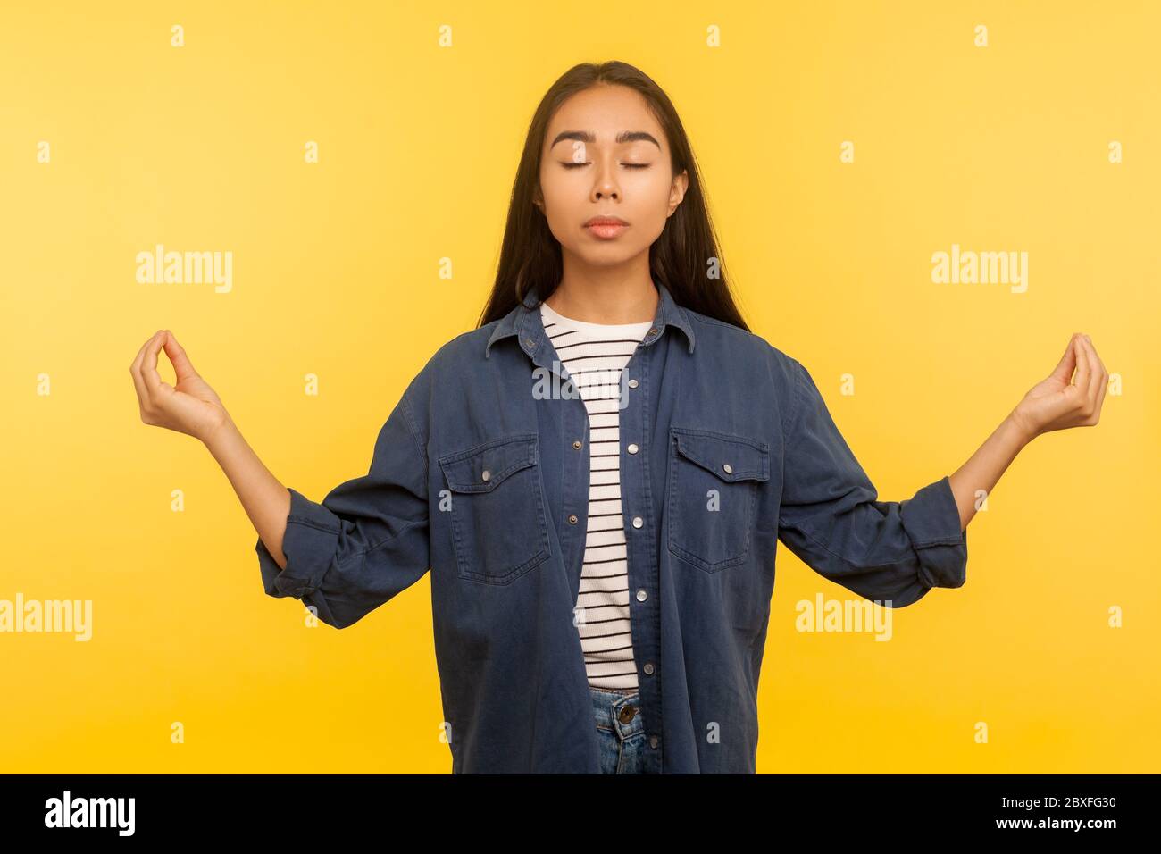 Peaceful mind. Portrait of woman in denim shirt meditating with mudra ...