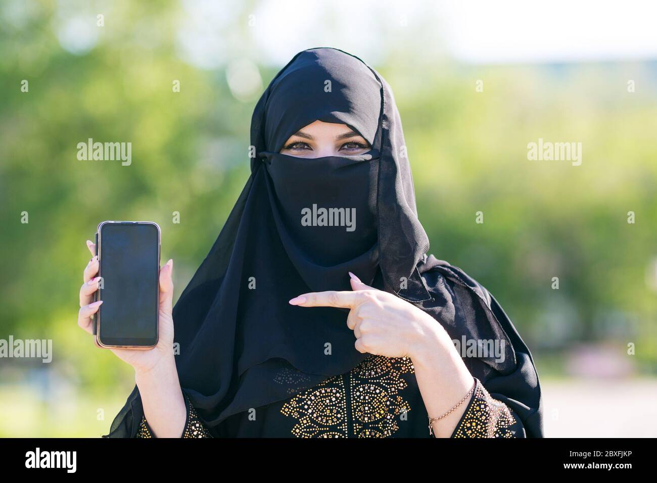 Islamic muslim woman holds modern mobile phone in her hand. Cellular ...