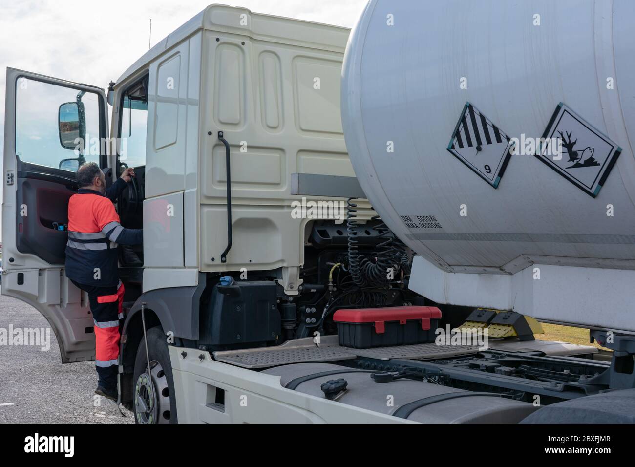Dangerous goods tank truck driver getting into the cab using the two ...