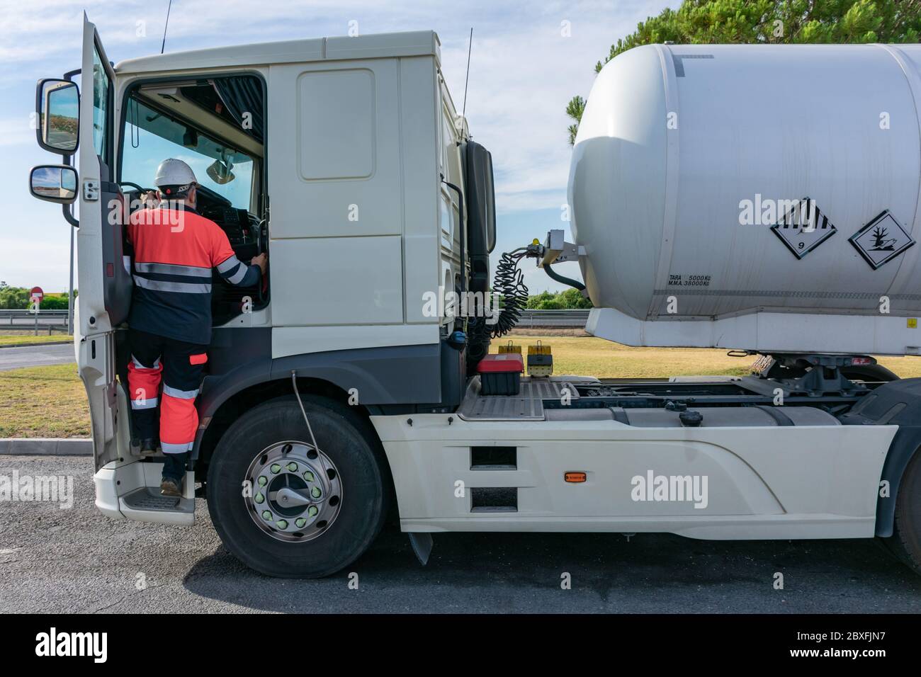 Dangerous goods tank truck driver getting into the cab using the two ...