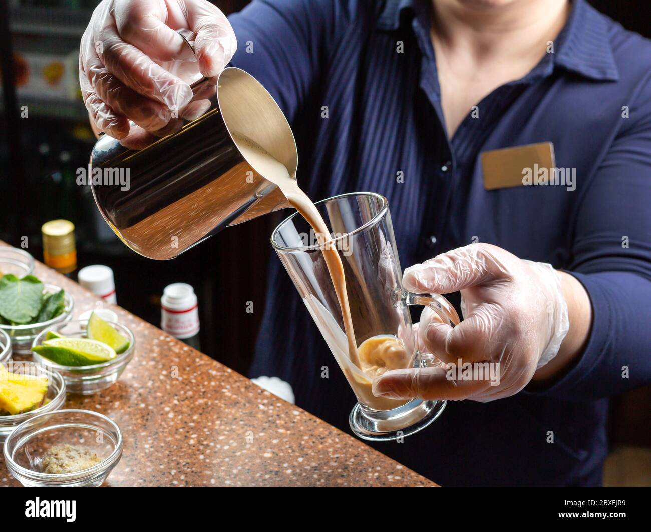 The bartender stands behind the bar and pours a coffee drink from a ...
