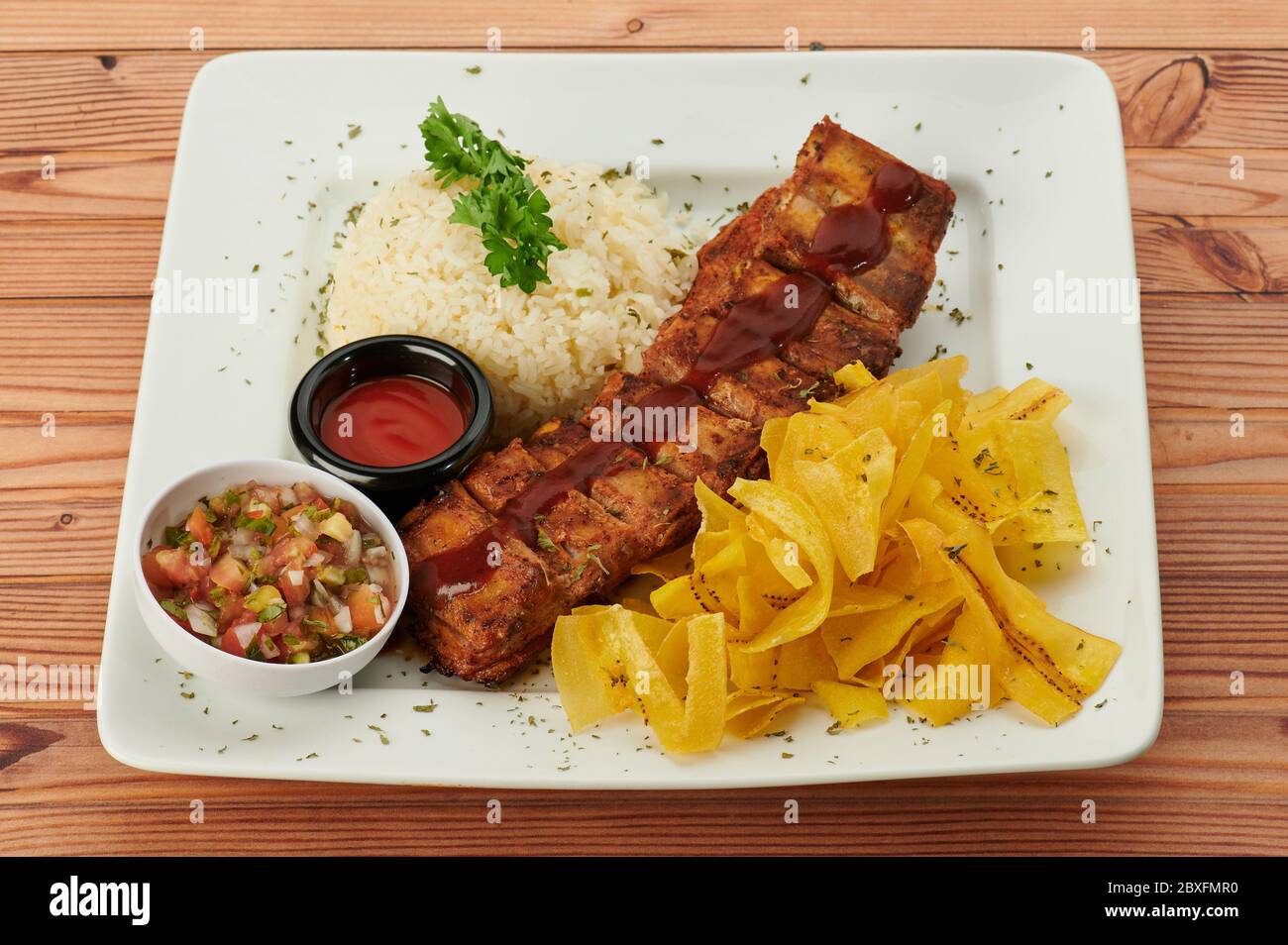 Plate with bbq ribs and garnish on wooden table side view Stock Photo ...