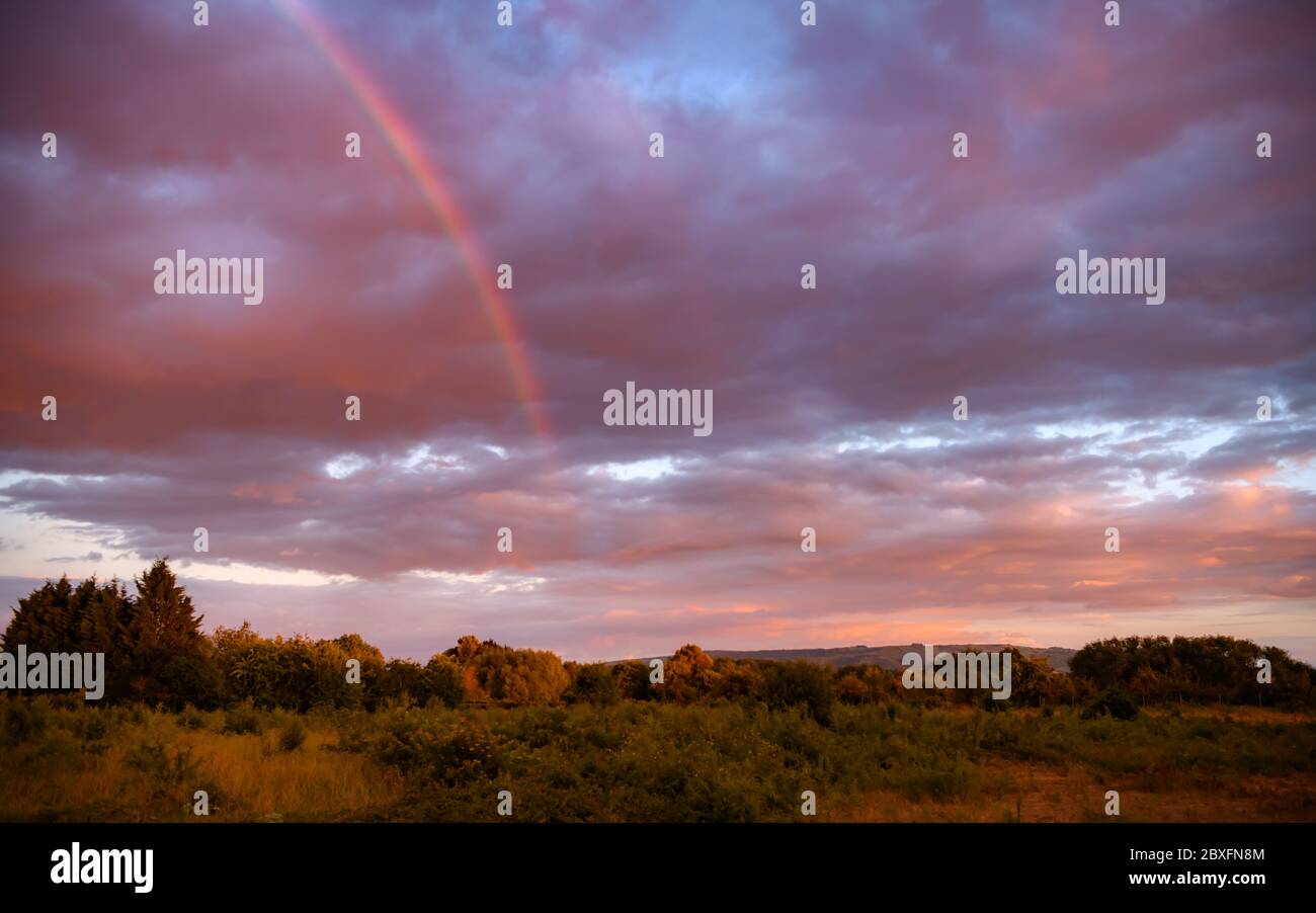 Sunset landscape with rainbow Stock Photo - Alamy