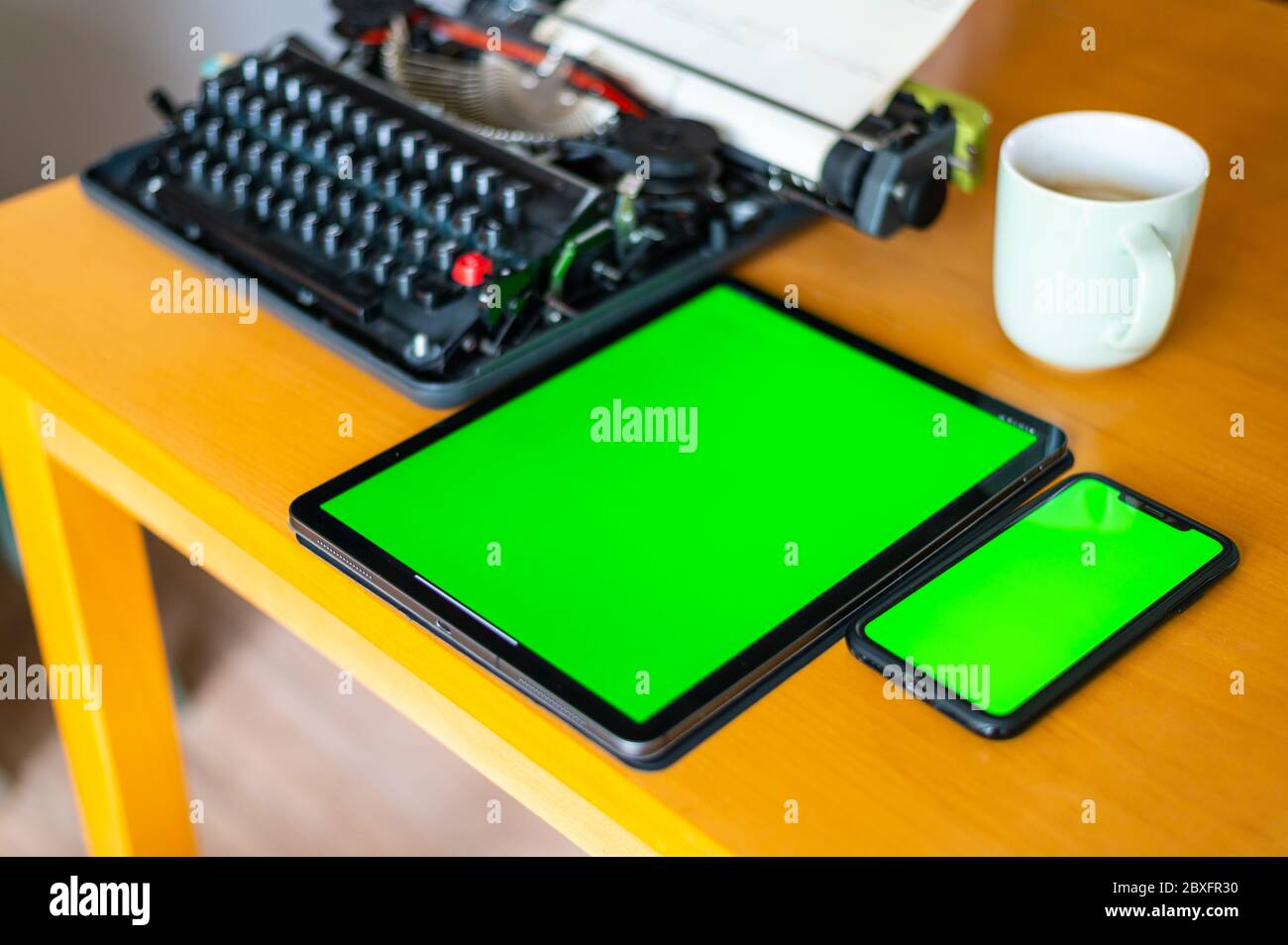 next to an old typewriter lies a tablet with a green screen on the ...