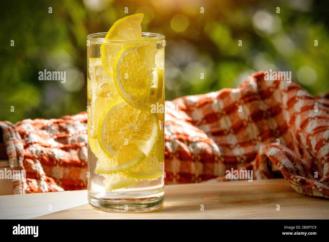 Glass of lemonade with lemon on sunny garden background Stock Photo - Alamy