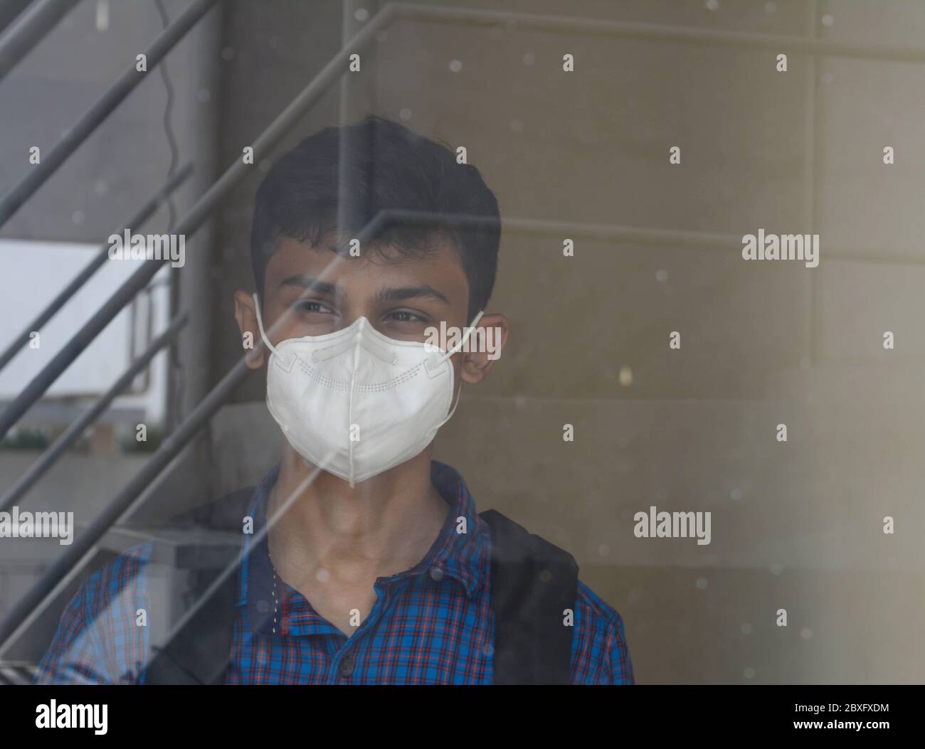 Young teen college student wearing face mask in front of the window ...