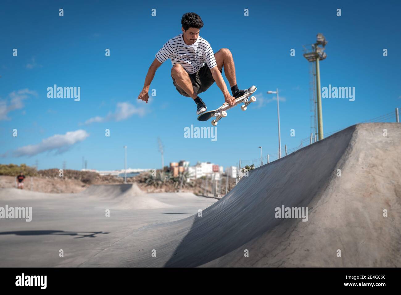 Young skateboarder man does a trick called `boneless` in a ramp of a ...