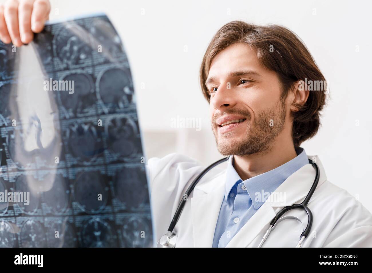 Positive doctor looking at x-ray scans of patient head Stock Photo - Alamy
