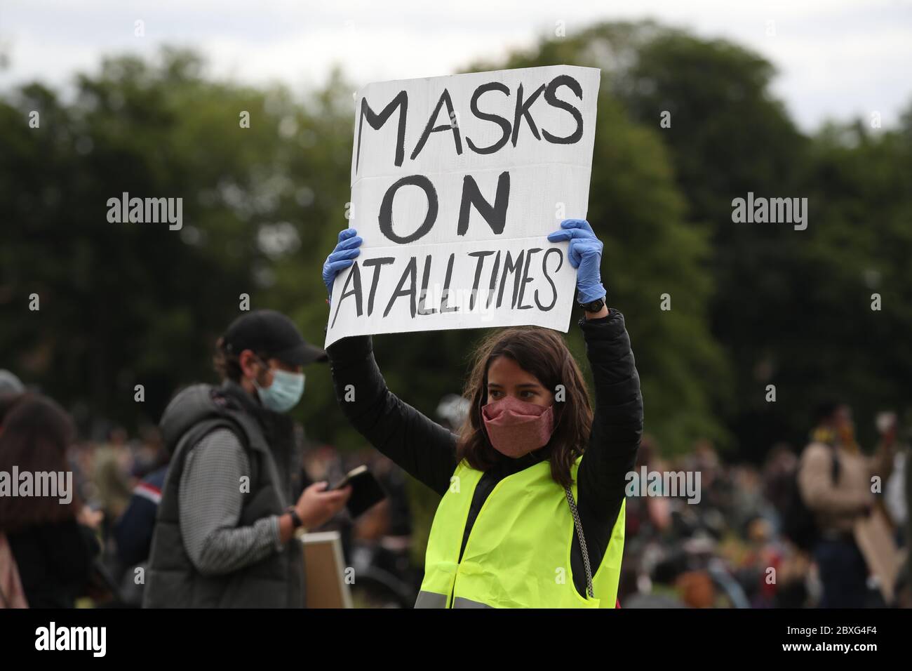 A steward reminding people to wear masks as they take part in a Black ...