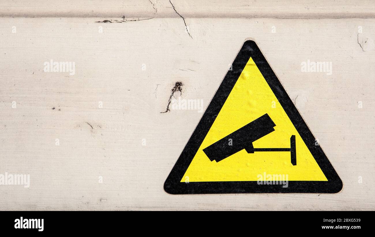 Yellow security camera sticker. Painted wooden facade. Procedures and ...