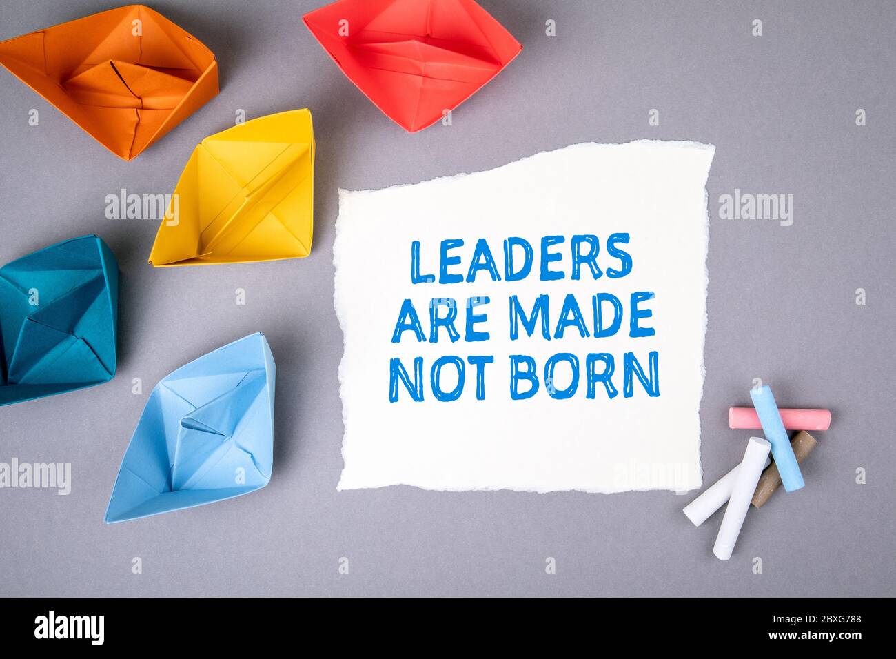 LEADERS ARE MADE NOT BORN. Text on note sheet, paper boats, symbol of ...