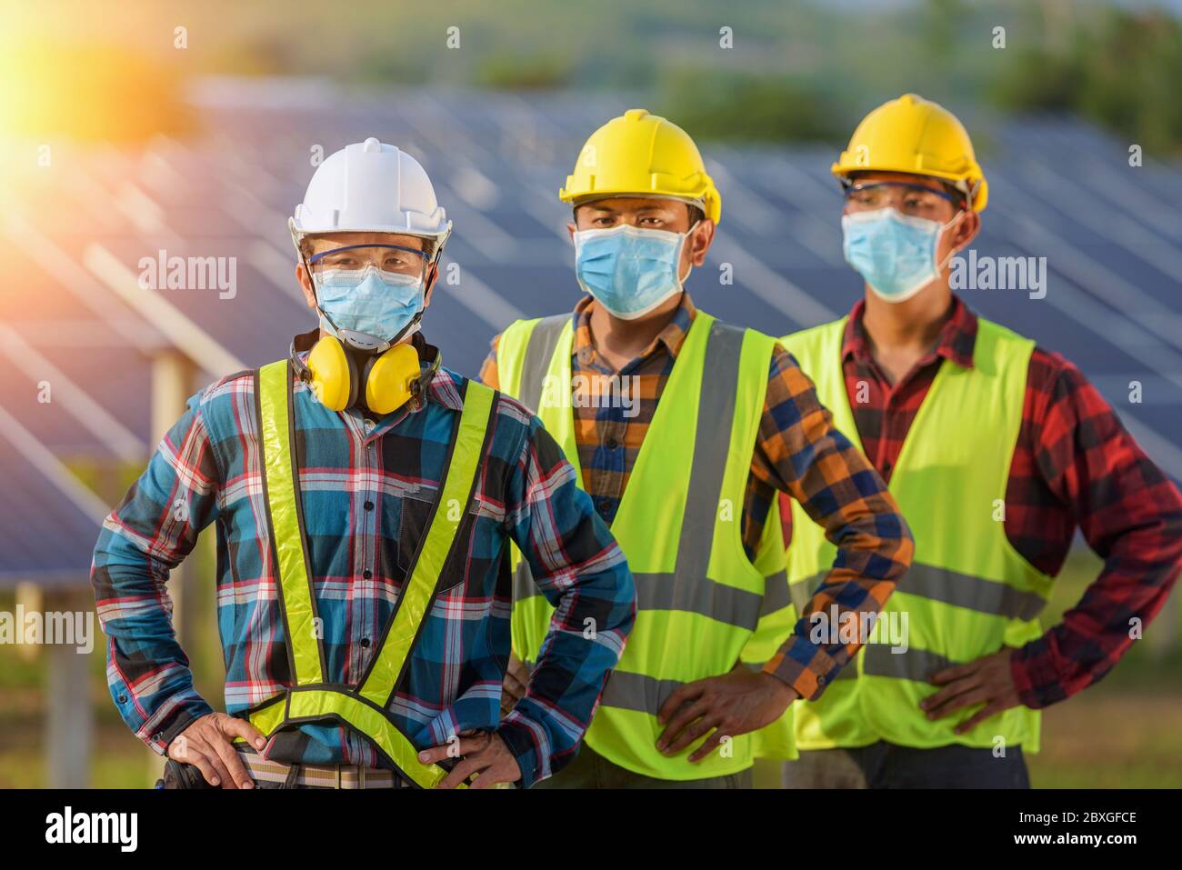 Portrait of three engineers on a construction site wearing face masks ...