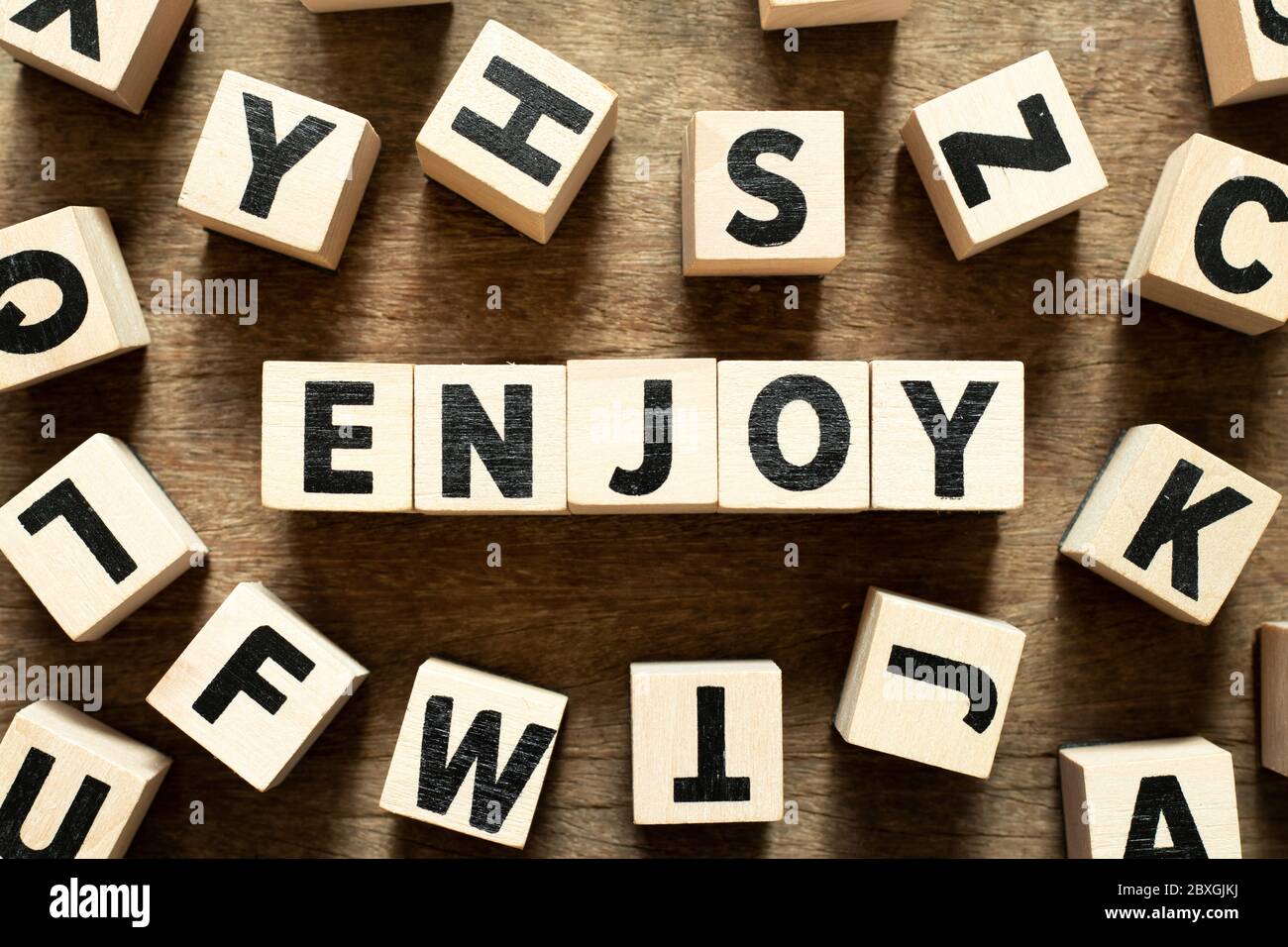 Letter block in word enjoy with another block on wood background Stock ...