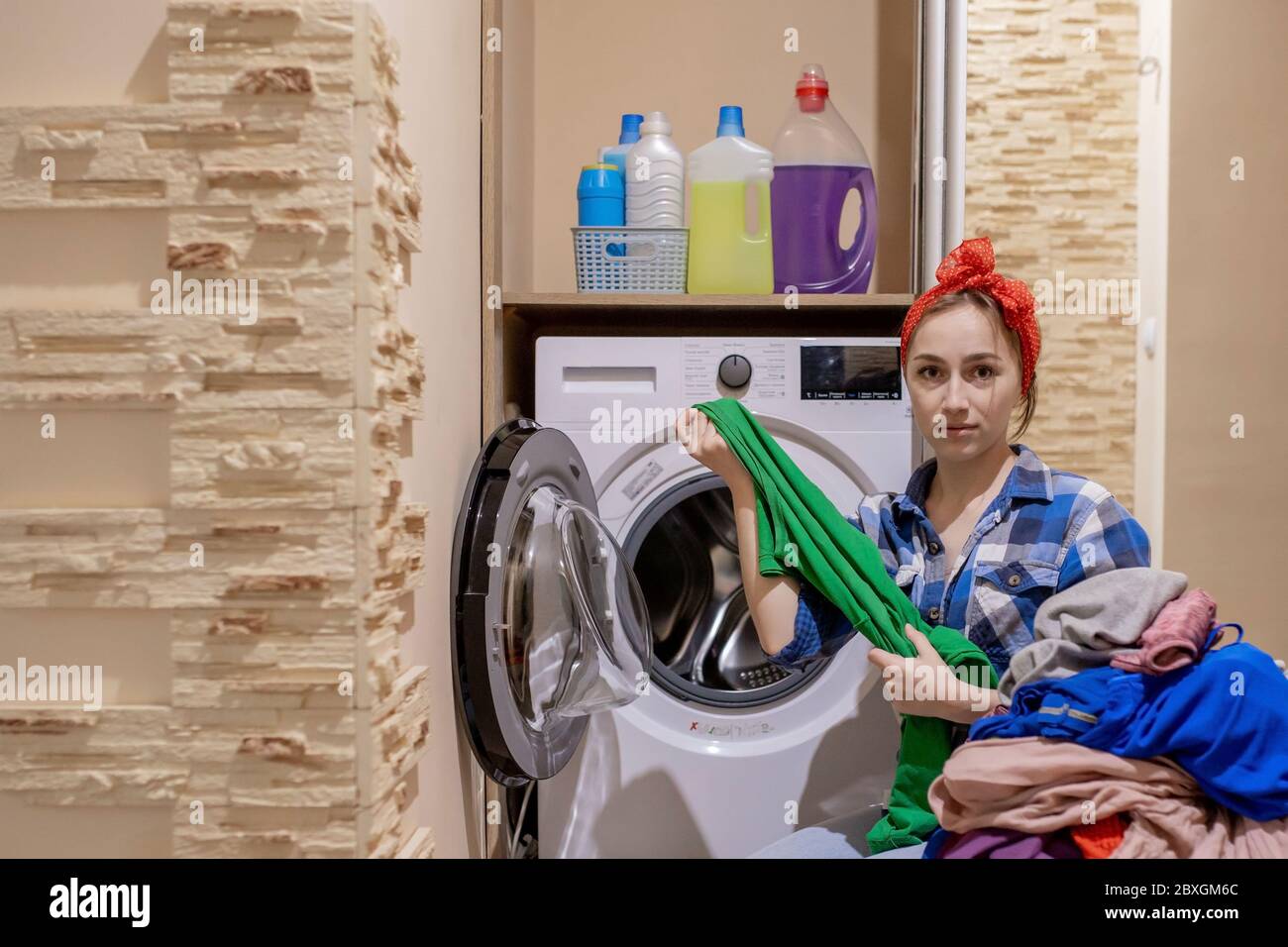 Beautiful young woman doing laundry. Housework Stock Photo - Alamy