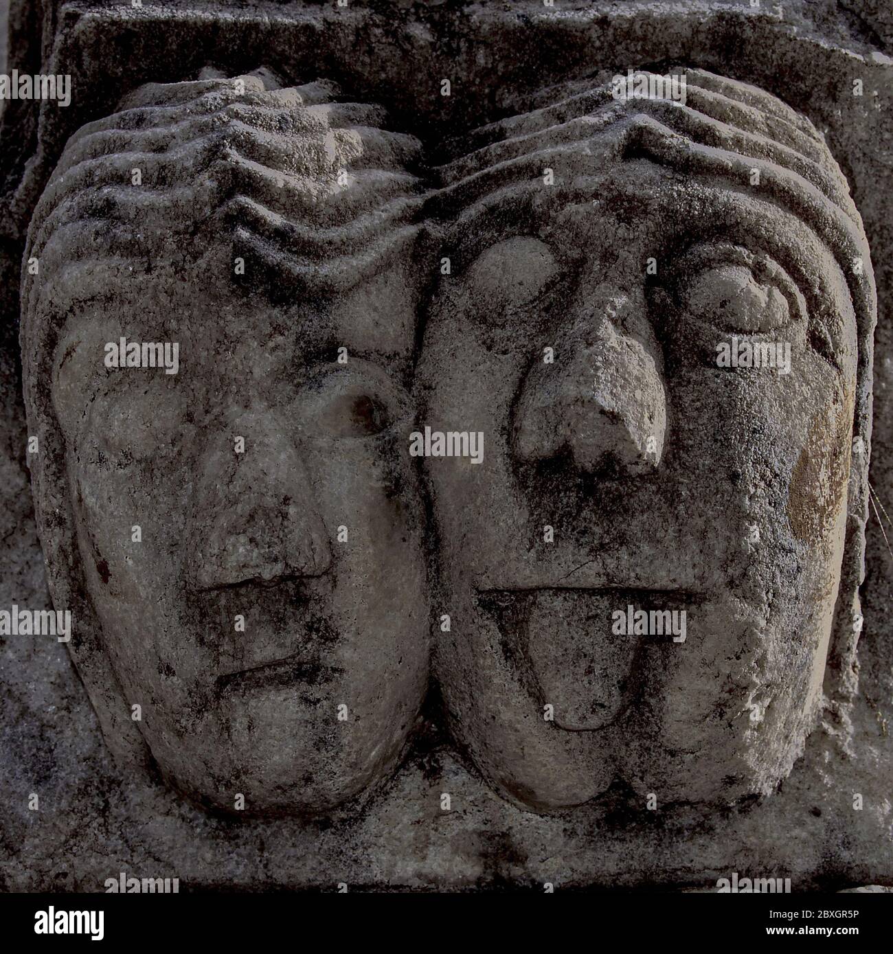 Grotesque faces stick out their tongues. Square detail of medieval ...