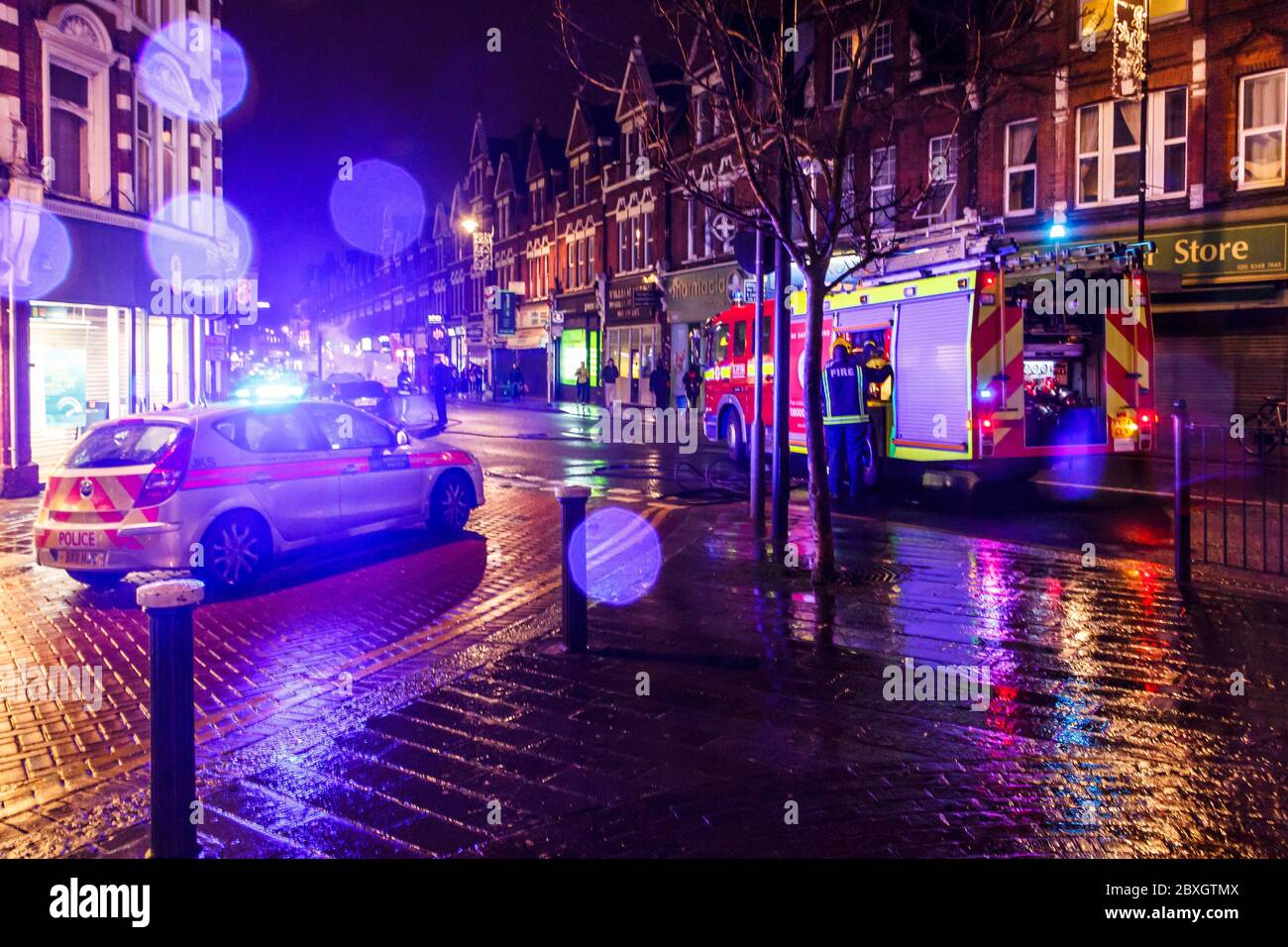 A police car and fire engine attending a vehicle fire on a rainy autumn ...