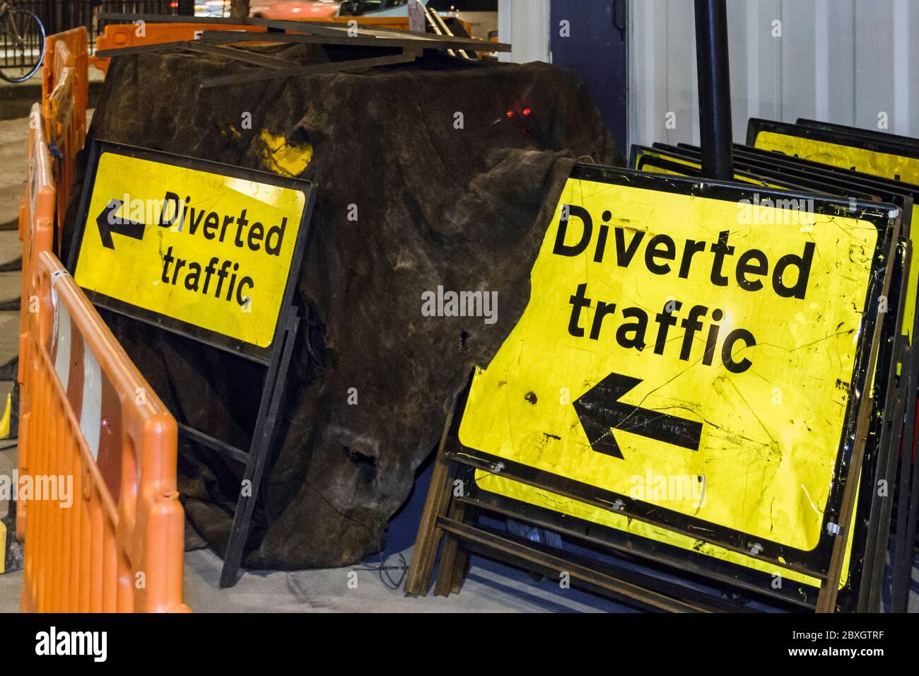 A stack of 'Diverted Traffic' signs by the side of the road at night ...