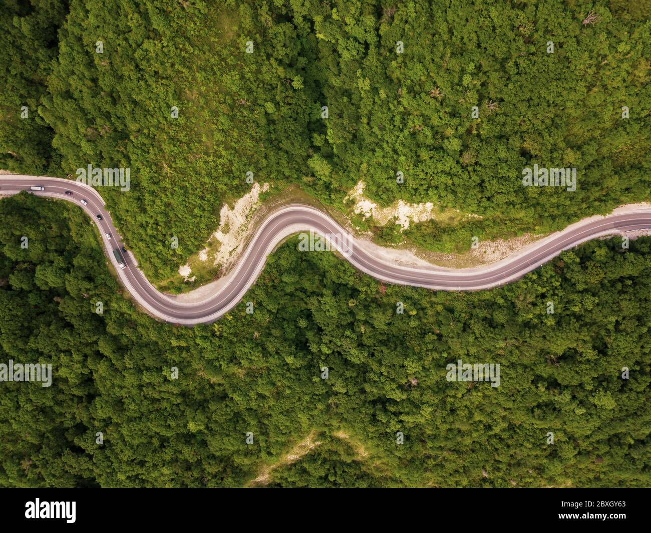Aerial top down view: of cars driving on zig zag winding mountain road ...