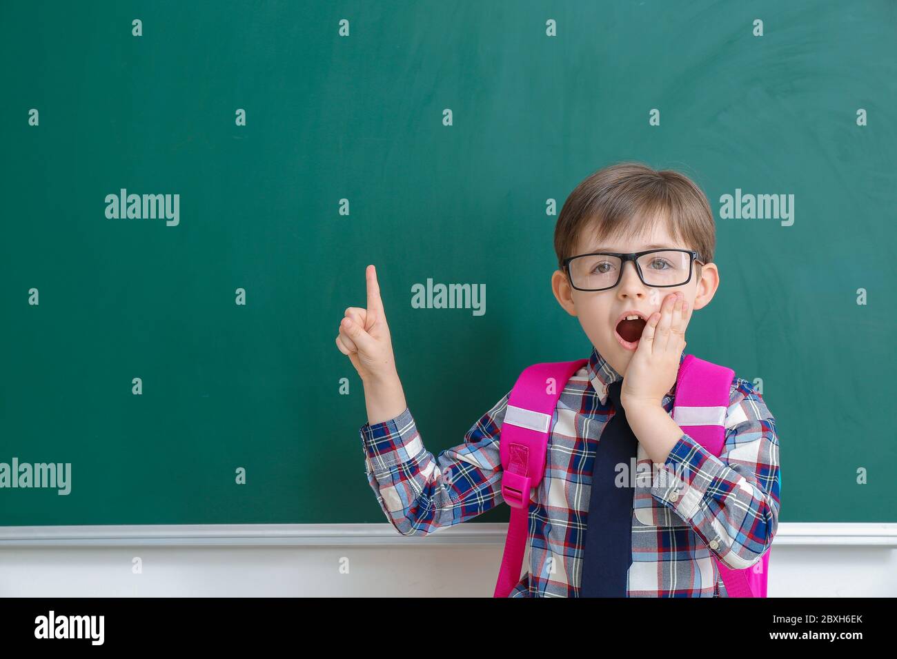 Cute little schoolboy pointing at blackboard in classroom Stock Photo ...