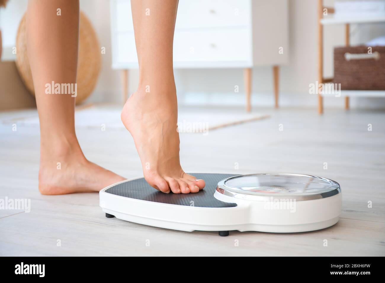 Young woman measuring her weight at home Stock Photo - Alamy