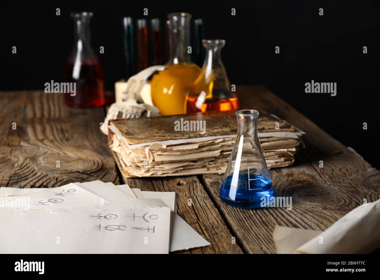 Potions and old book on alchemist's table Stock Photo - Alamy