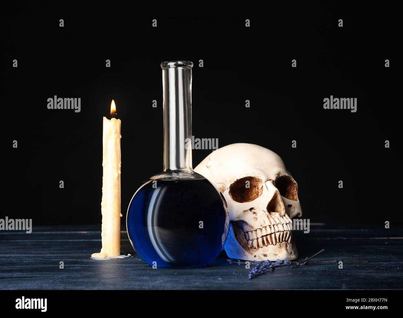 Human skull, candle and potion on alchemist's table Stock Photo - Alamy