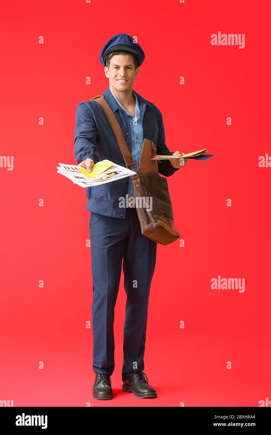 Handsome young postman on color background Stock Photo - Alamy