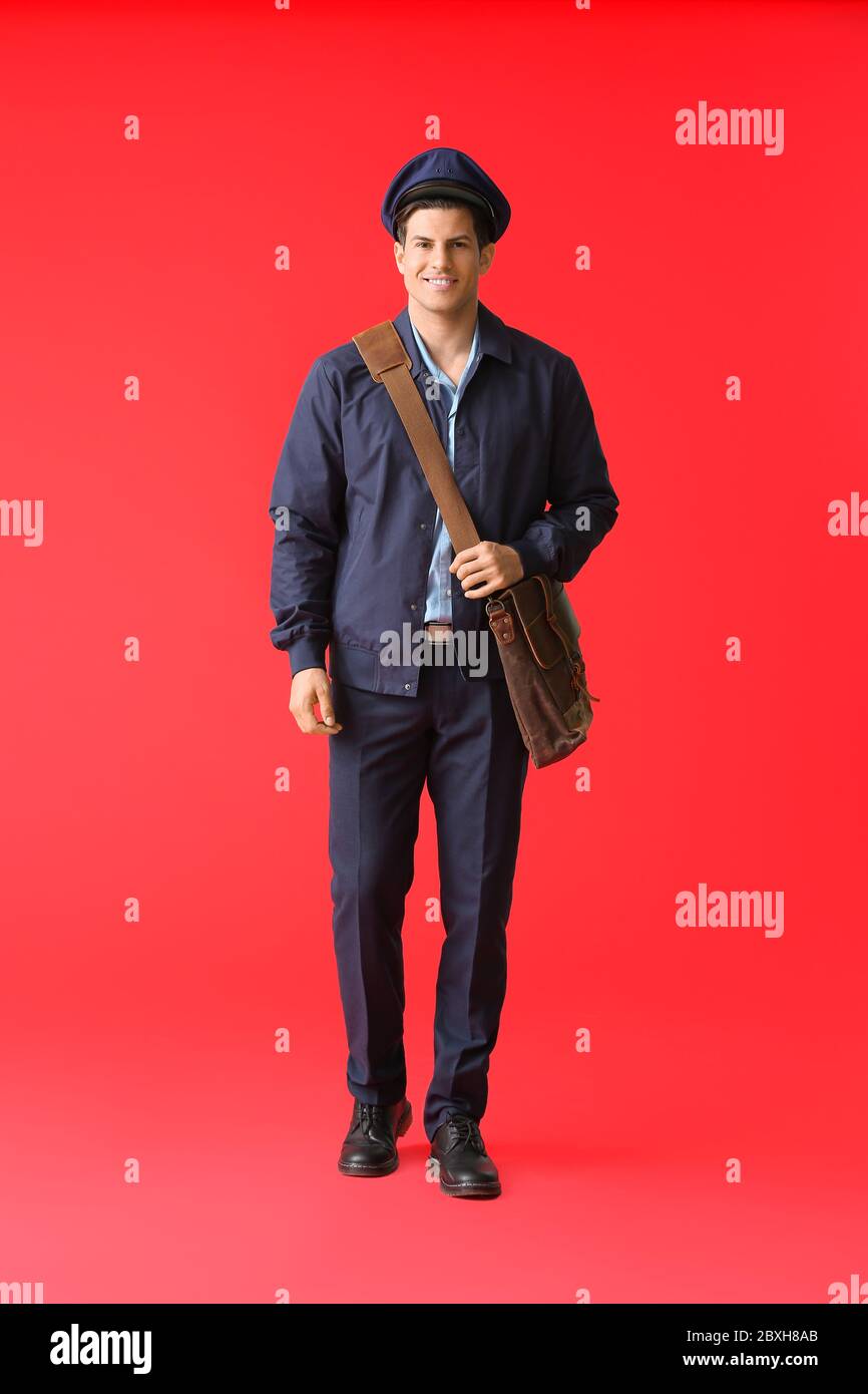 Handsome young postman on color background Stock Photo - Alamy