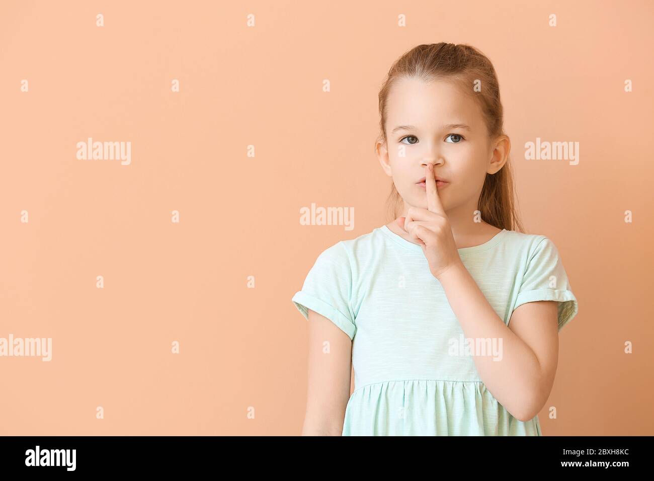 Cute little girl showing silence gesture on color background Stock ...