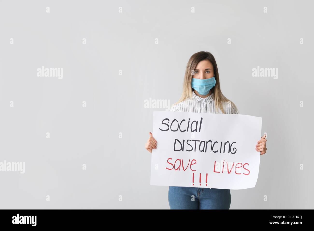 Young woman holding paper with text SOCIAL DISTANCE. SAVE LIVES on ...