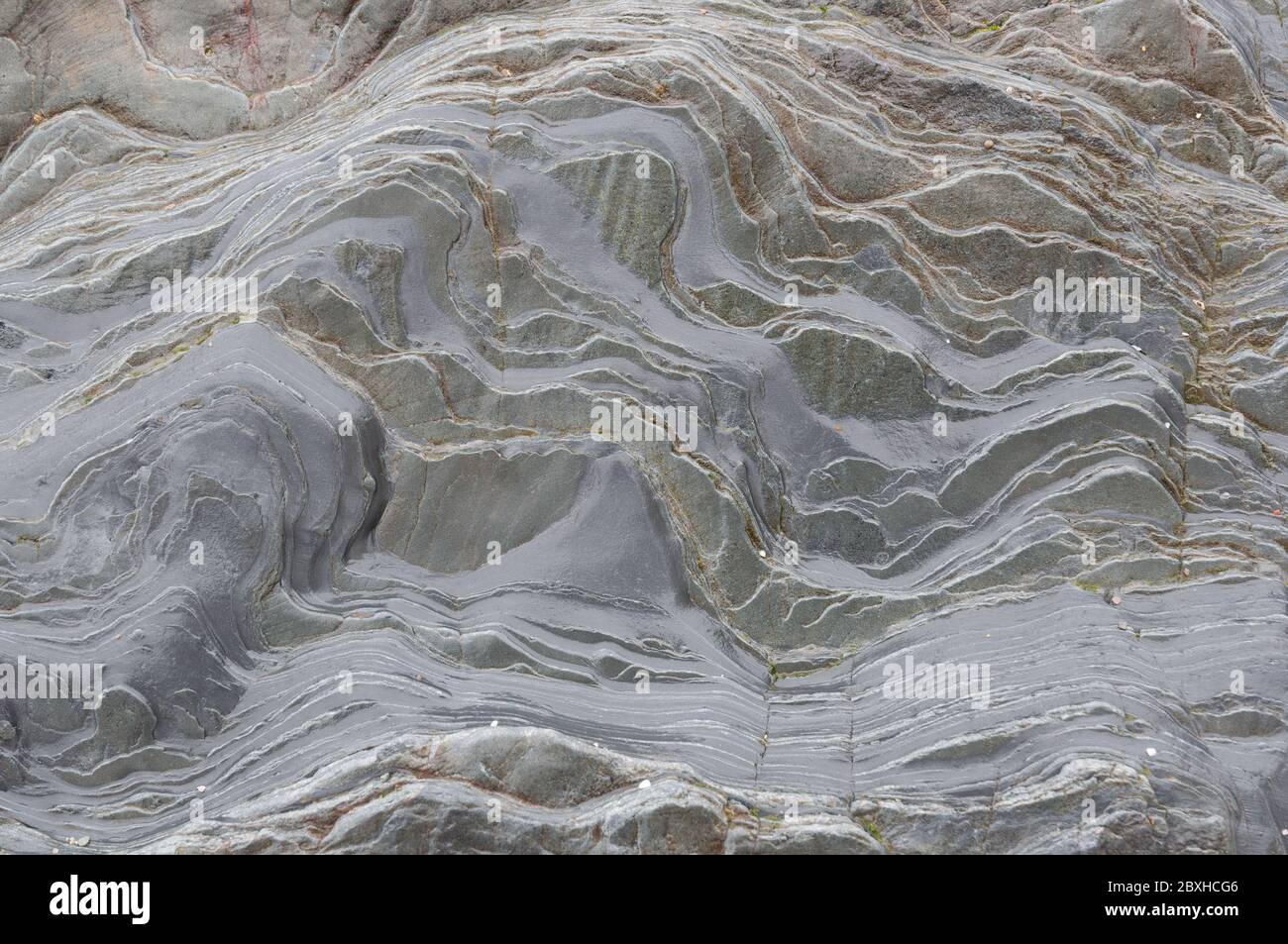 Many layers visible in partially eroded strata of smooth grey slate ...
