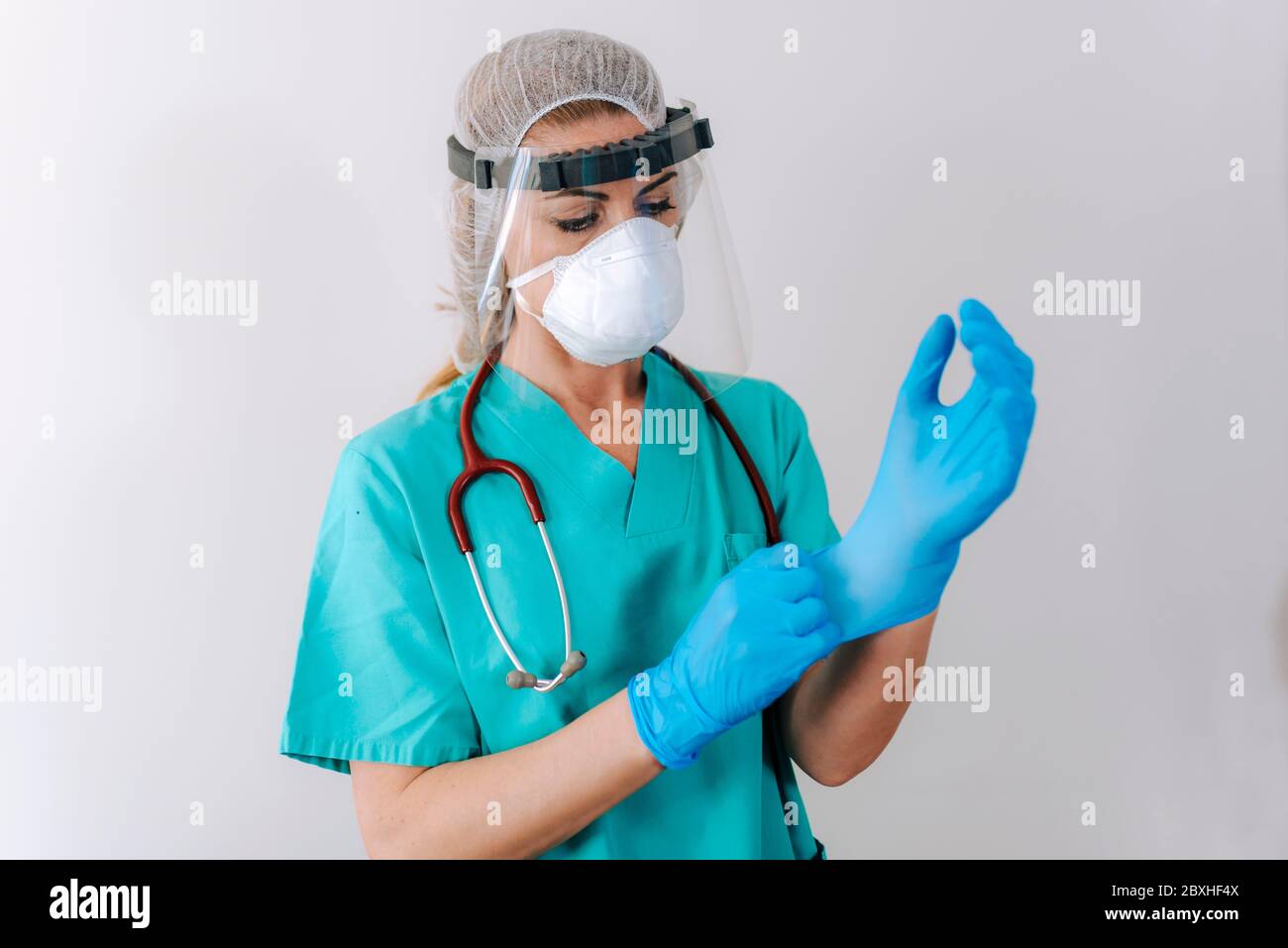 Female nurse with a mask putting on gloves Stock Photo - Alamy