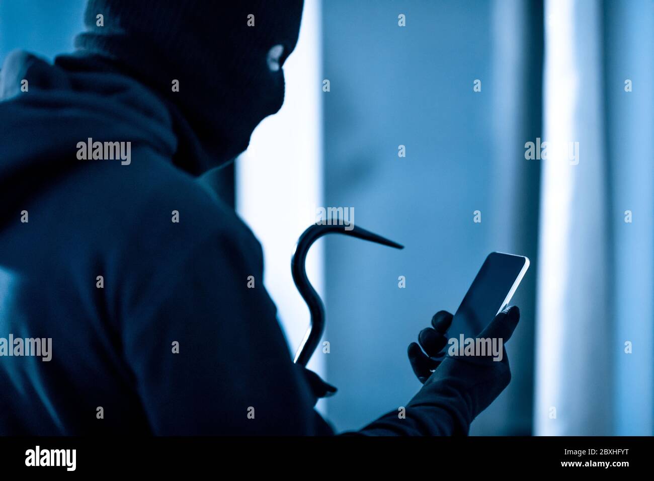 Villain holding crowbar and smartphone preparing burglary Stock Photo ...
