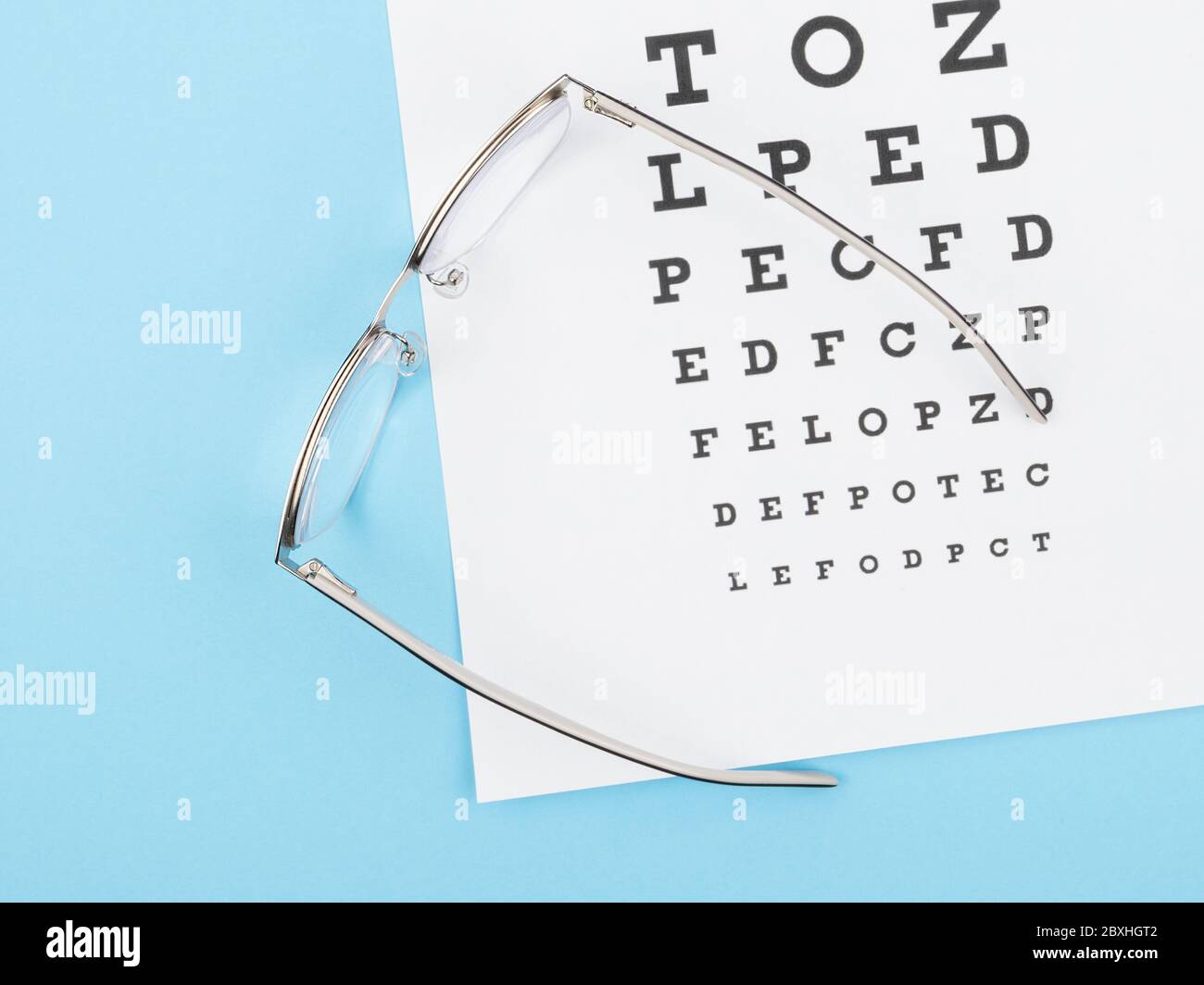 Glasses and optician chart on a blue background Stock Photo - Alamy
