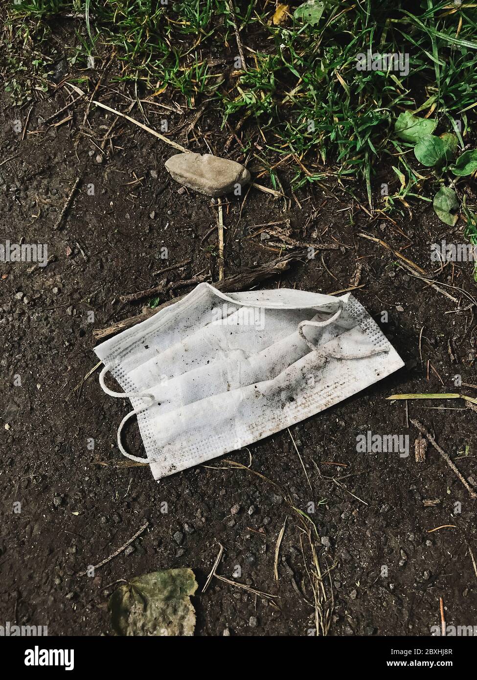 Disposable dirty face mask on ground, single use plastic trash on grass ...