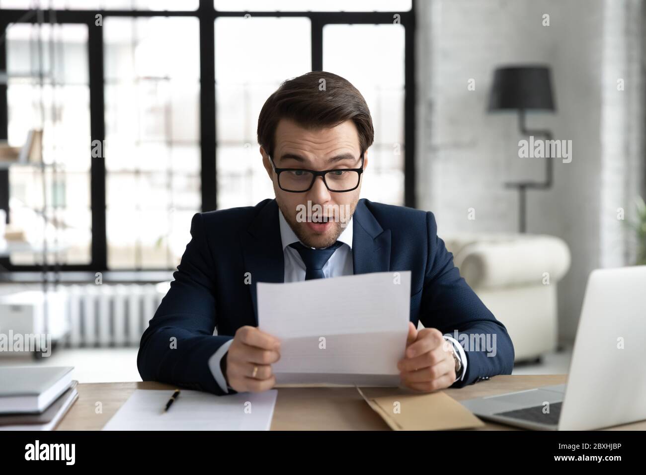 Surprised male employer shocked by letter correspondence Stock Photo ...