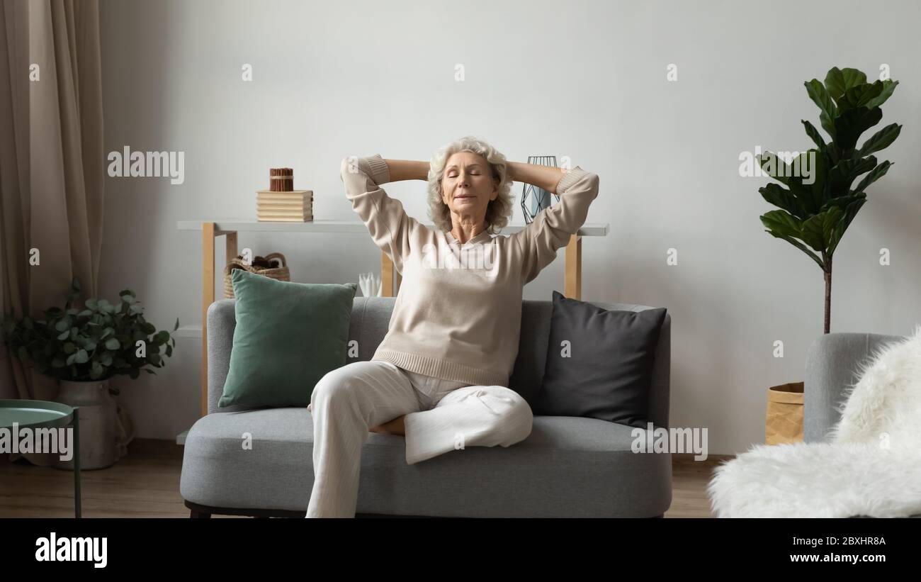 Peaceful elderly woman relax on couch meditating Stock Photo - Alamy