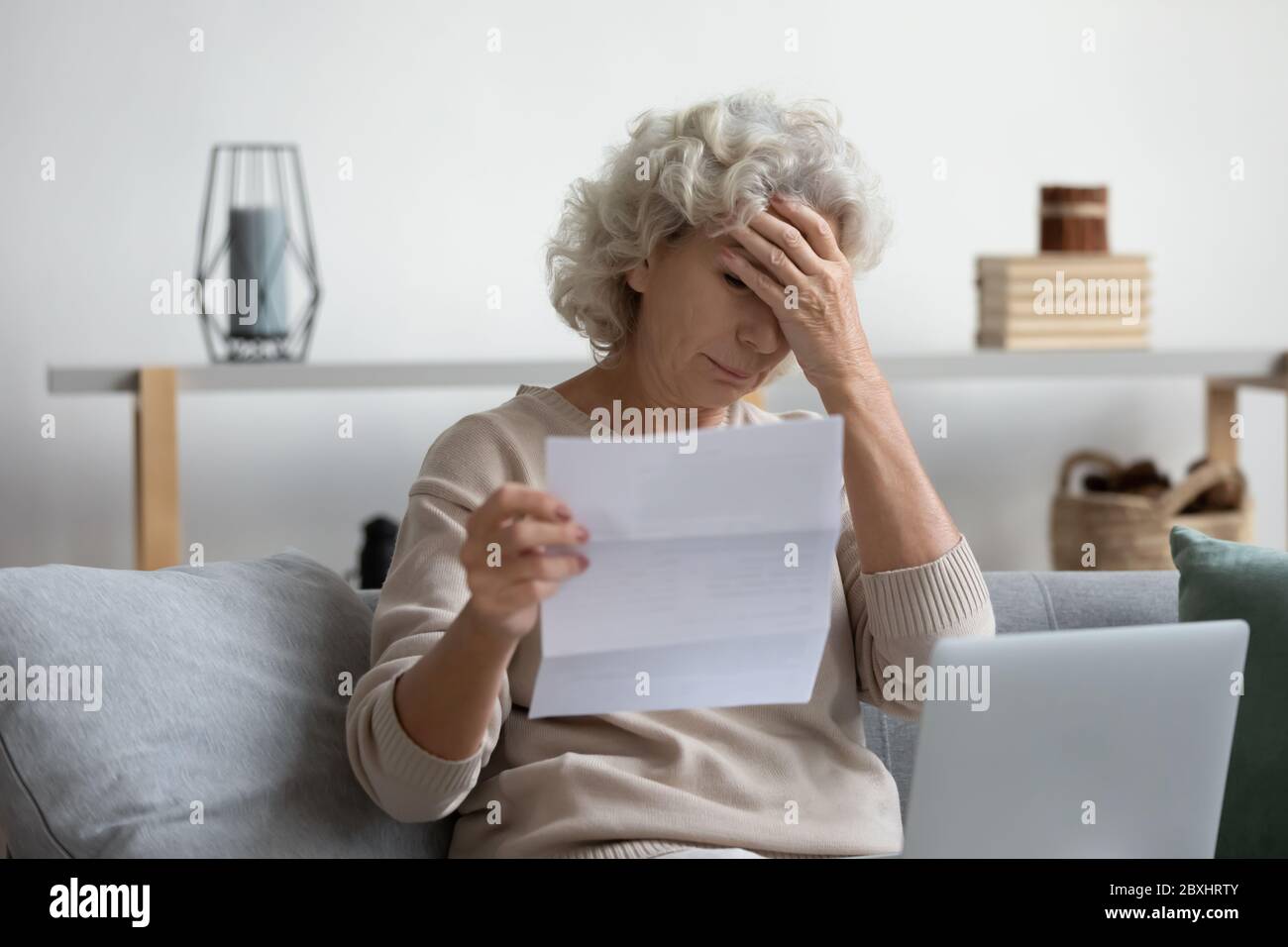 Sad mature woman disappointed by bad news in letter Stock Photo - Alamy