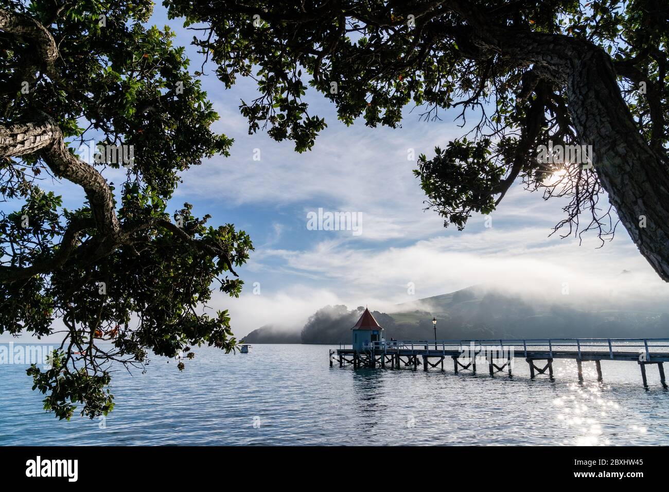 Wooden pier and sailboat at Akaroa harbor, New Zealand. Clear sky with ...