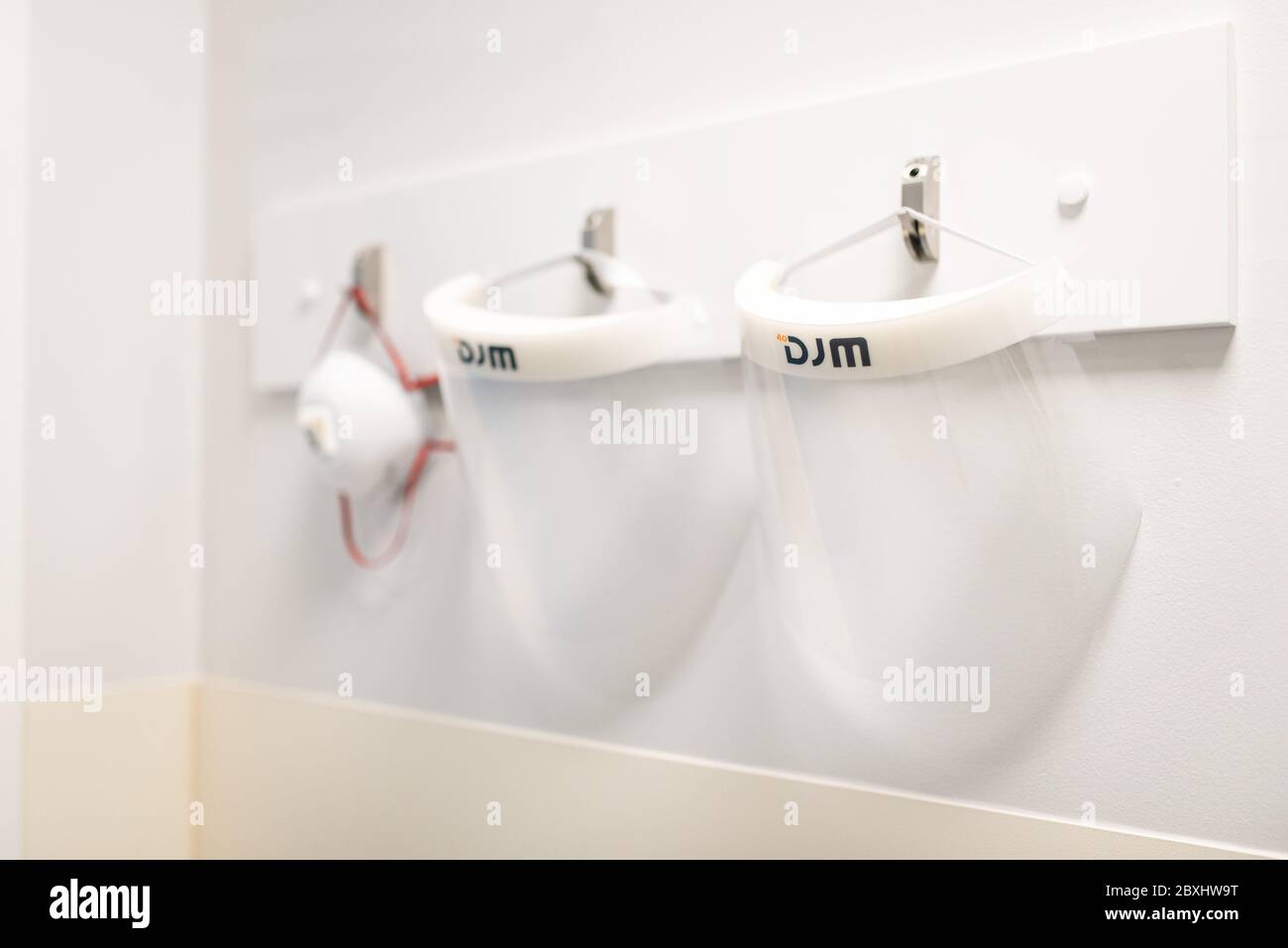 FFP3 face mask & visors hanging from hospital hook against white wall ...