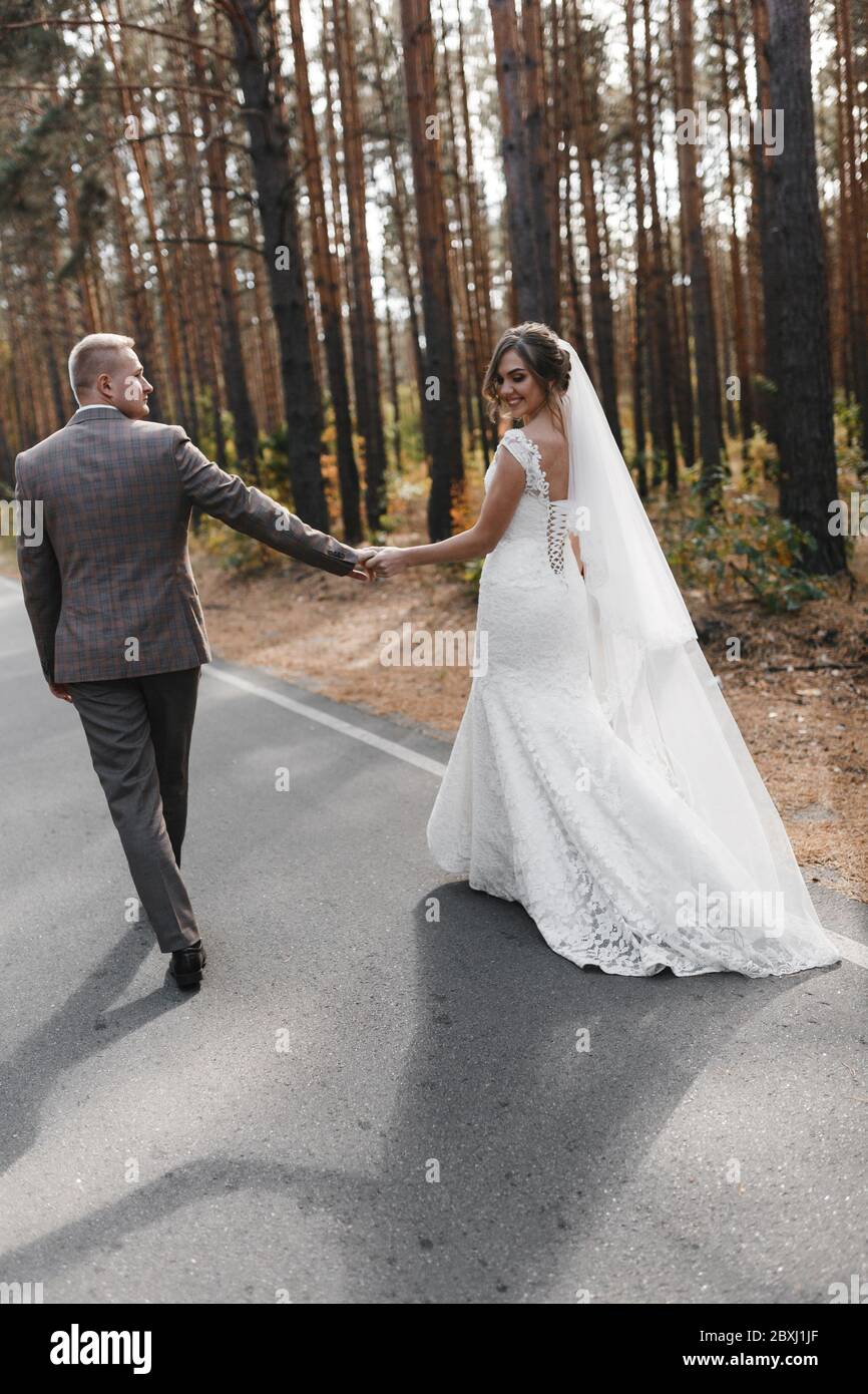 Bride and groom going on the road in the forest photographed from the ...