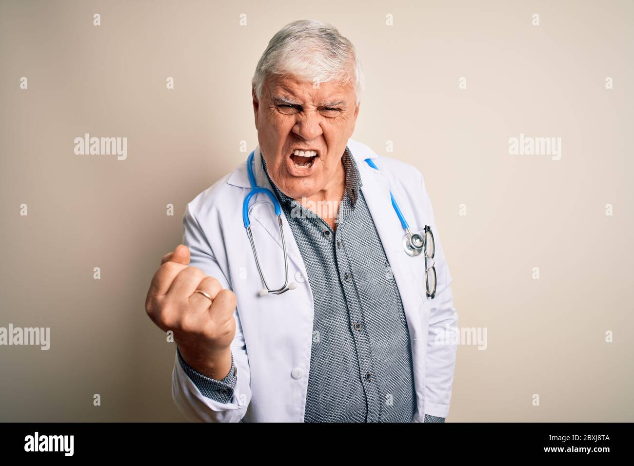 Senior handsome hoary doctor man wearing coat and stethoscope over ...