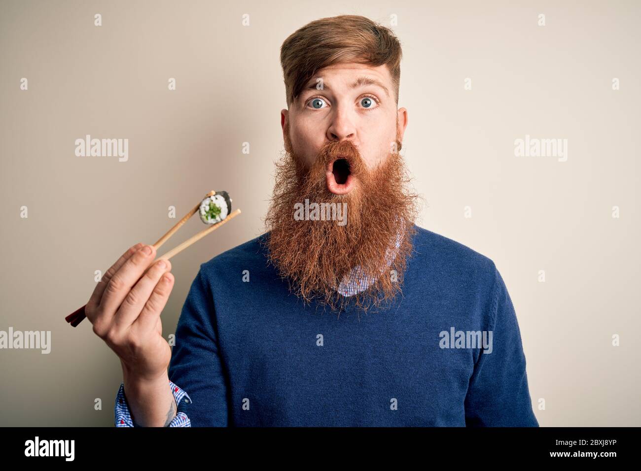 Redhead Irish man with beard eating green maki sushi using chopsticks ...