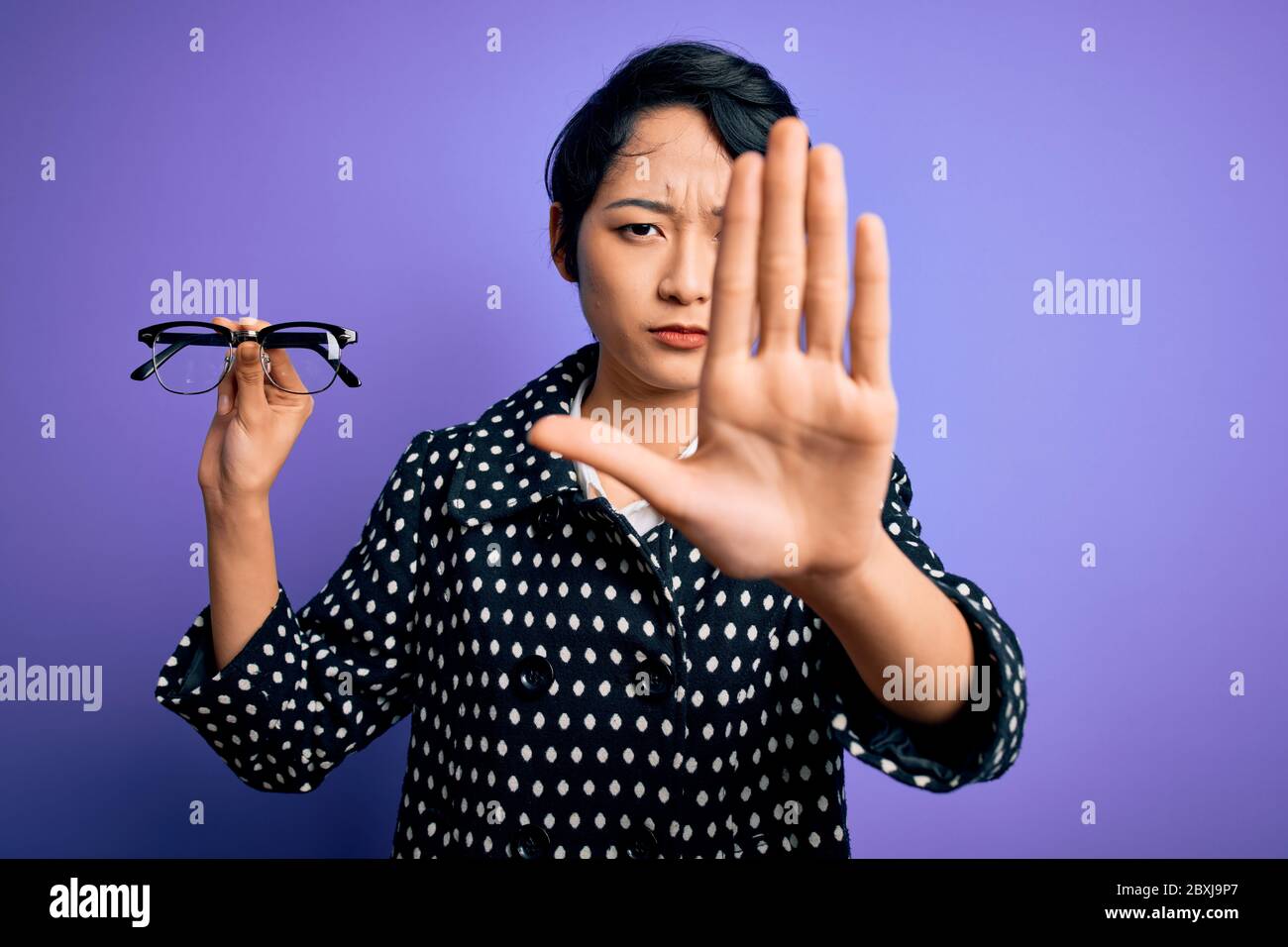 Young beautiful asian optical girl holding vision glasses over isolated ...