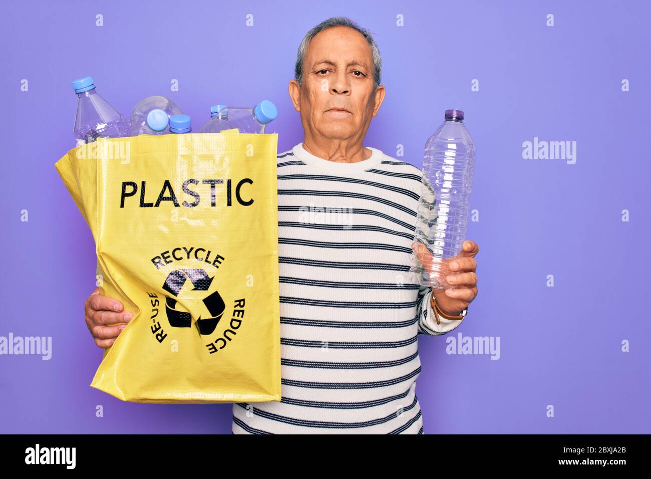 Senior man recycling holding bag with plastic bottles to recycle over ...