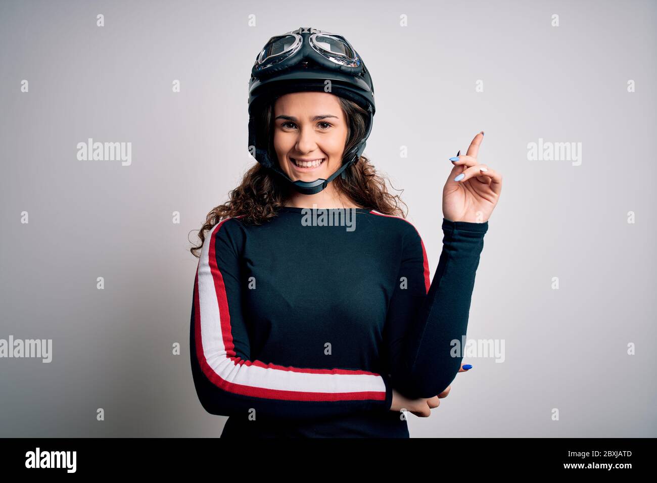 Beautiful motorcyclist woman with curly hair wearing moto helmet over ...