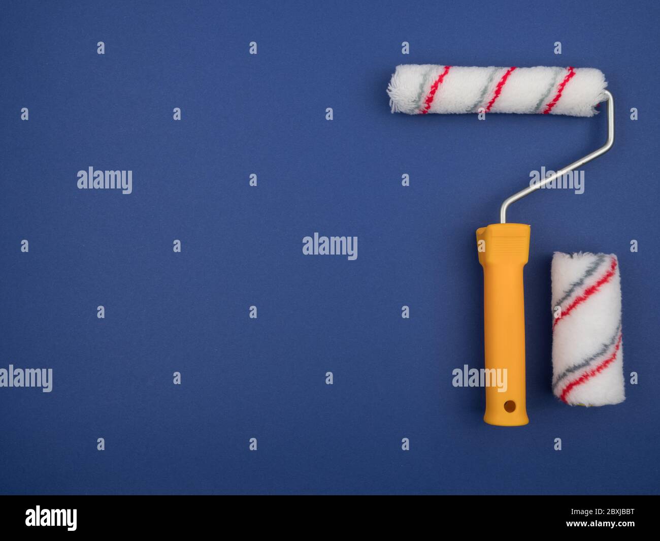 Paint rollers of different sizes on blue background Stock Photo - Alamy