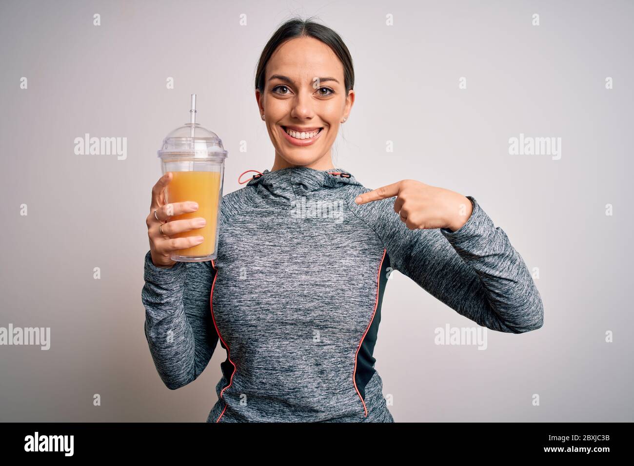 Young fitness woman wearing sport workout clothes drinking fresh orange ...