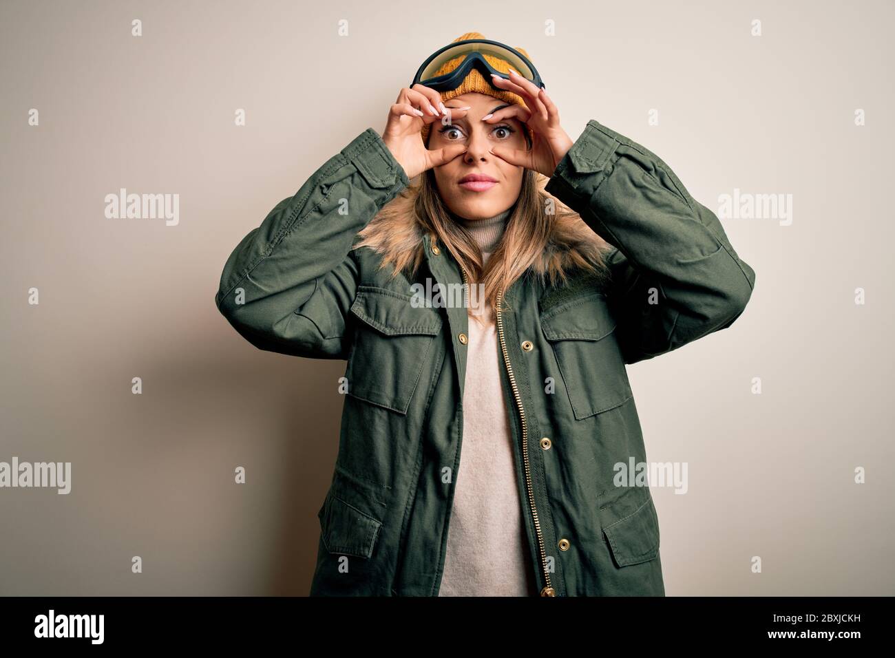 Young brunette skier woman wearing snow clothes and ski goggles over ...