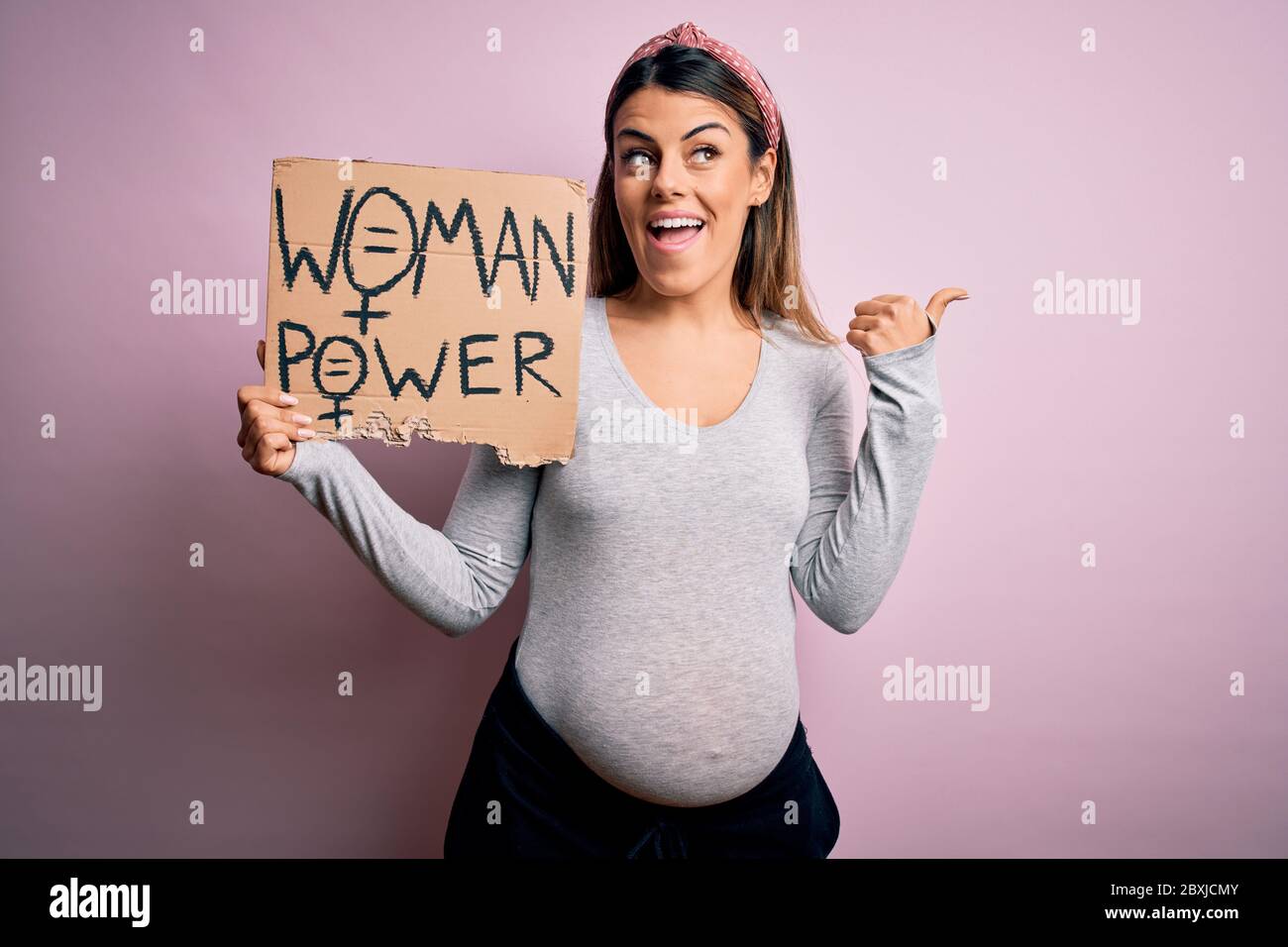 Young brunette woman pregnant expecting baby holding banner asking for ...